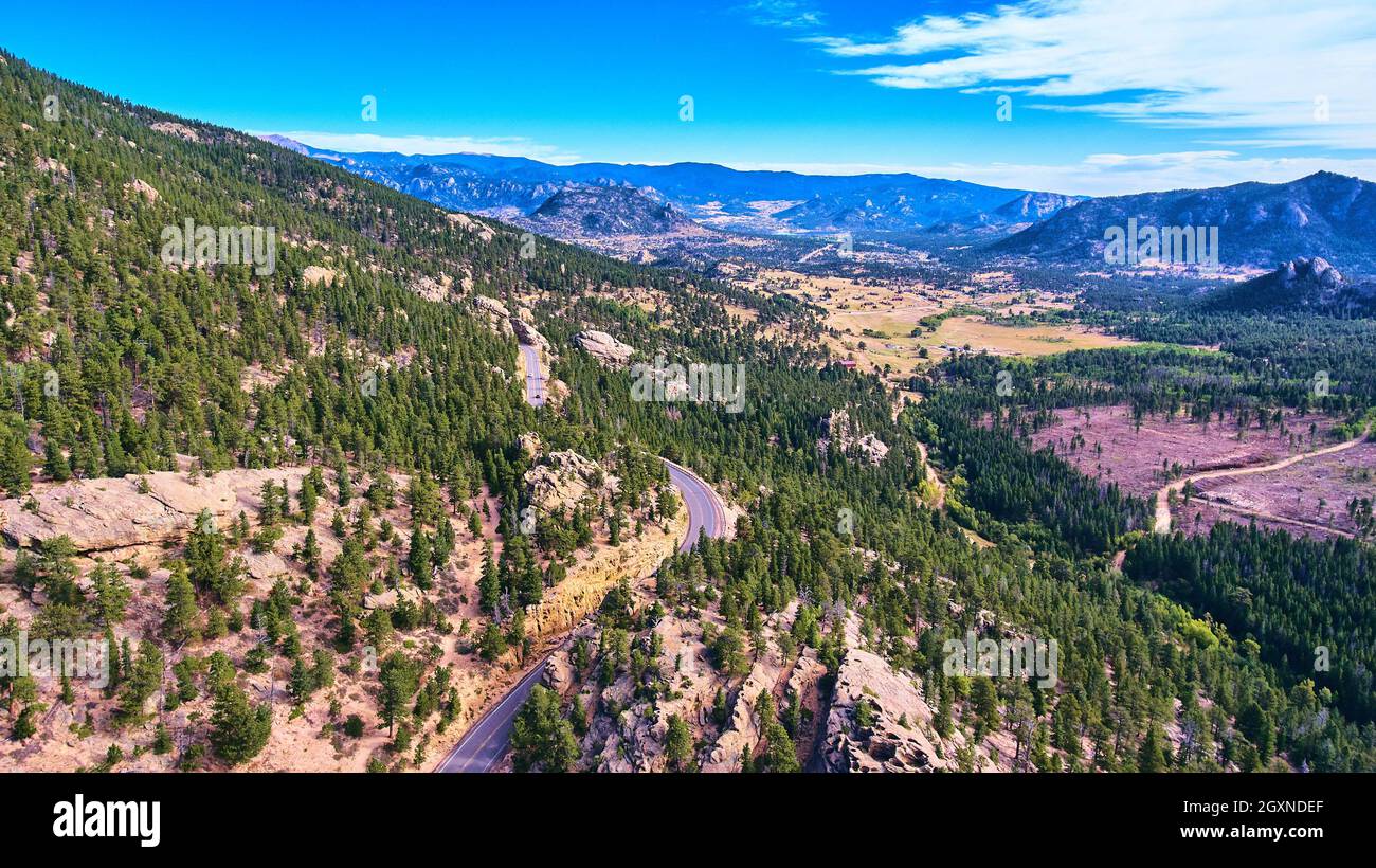Road winding through large mountains with pine trees Stock Photo - Alamy