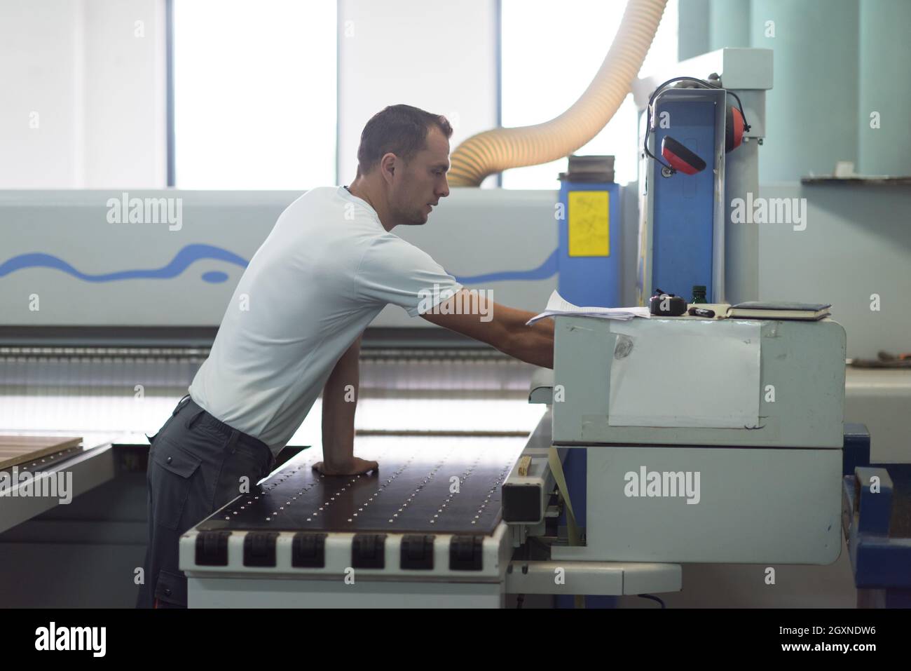 Young worker works in a factory for the production of wooden furniture ...