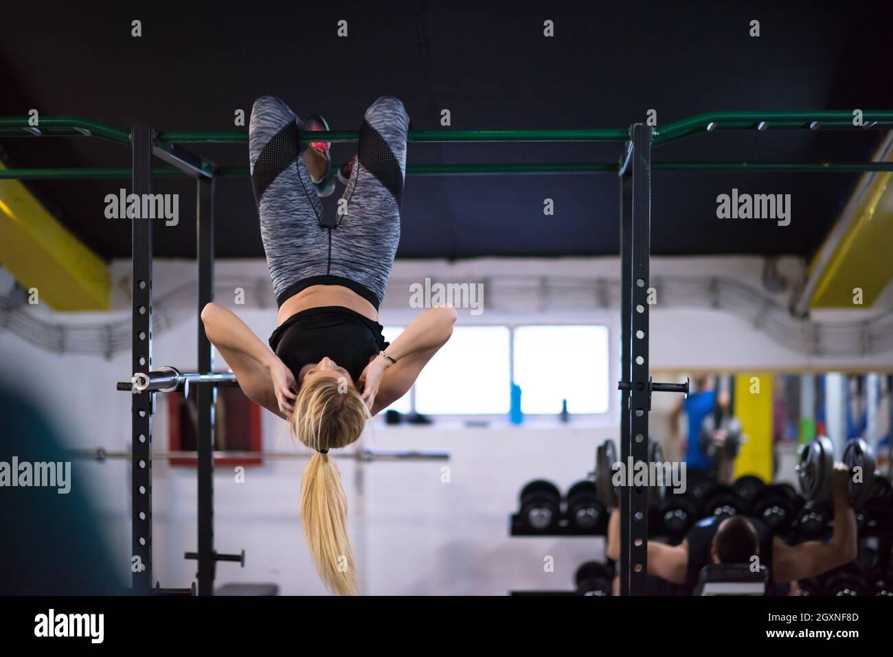 athlete woman doing abs exercises hanging upside down on horizontal bar ...