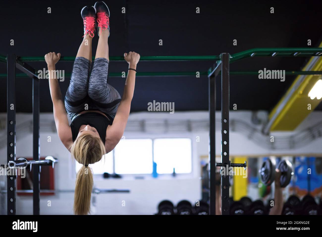 athlete woman doing abs exercises hanging upside down on horizontal bar ...