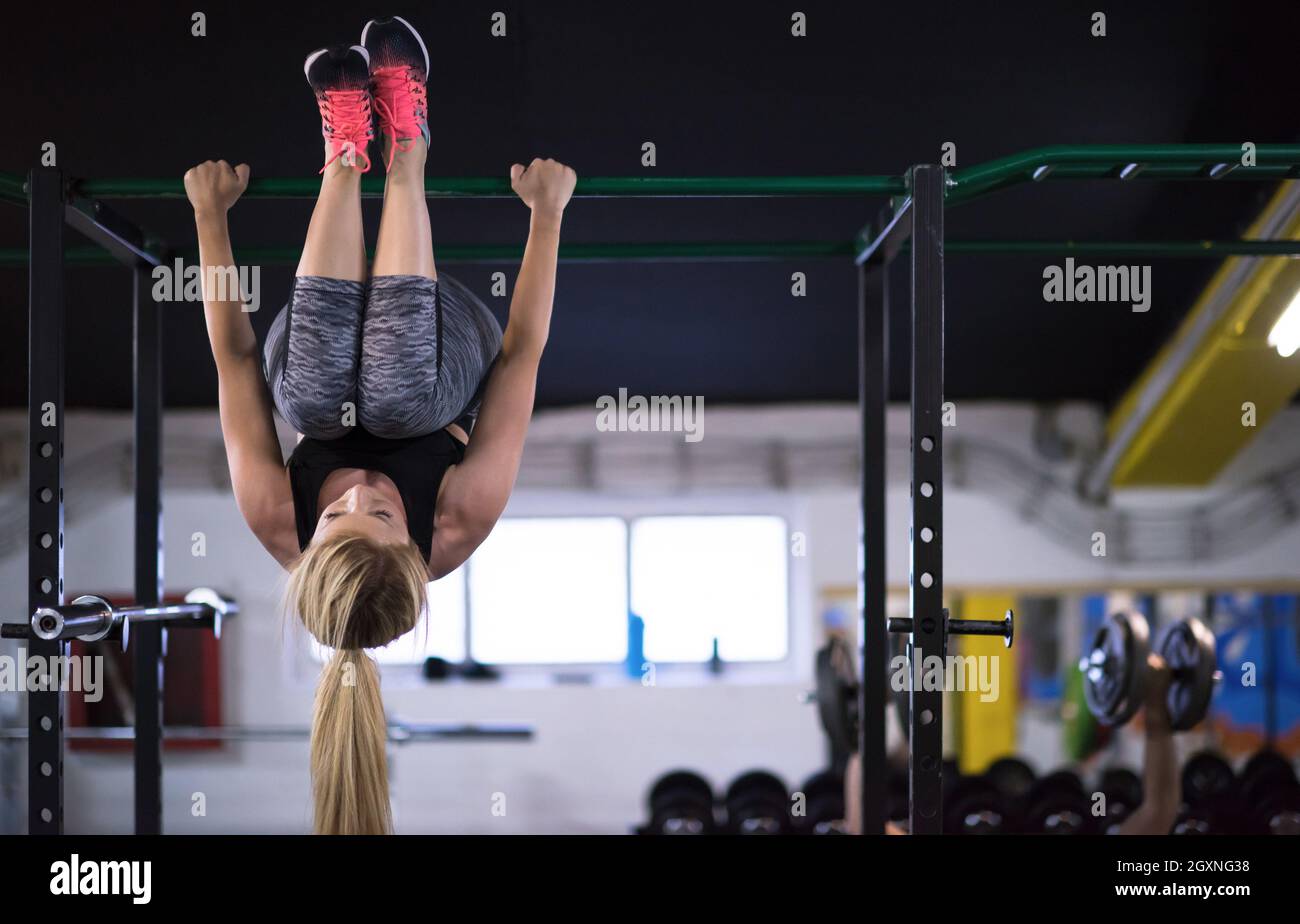 athlete woman doing abs exercises hanging upside down on horizontal bar ...