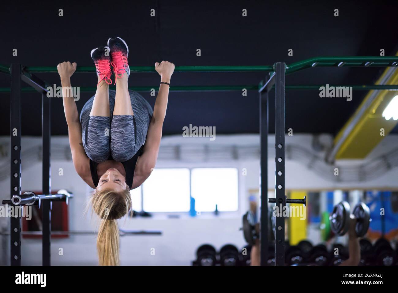 athlete woman doing abs exercises hanging upside down on horizontal bar ...