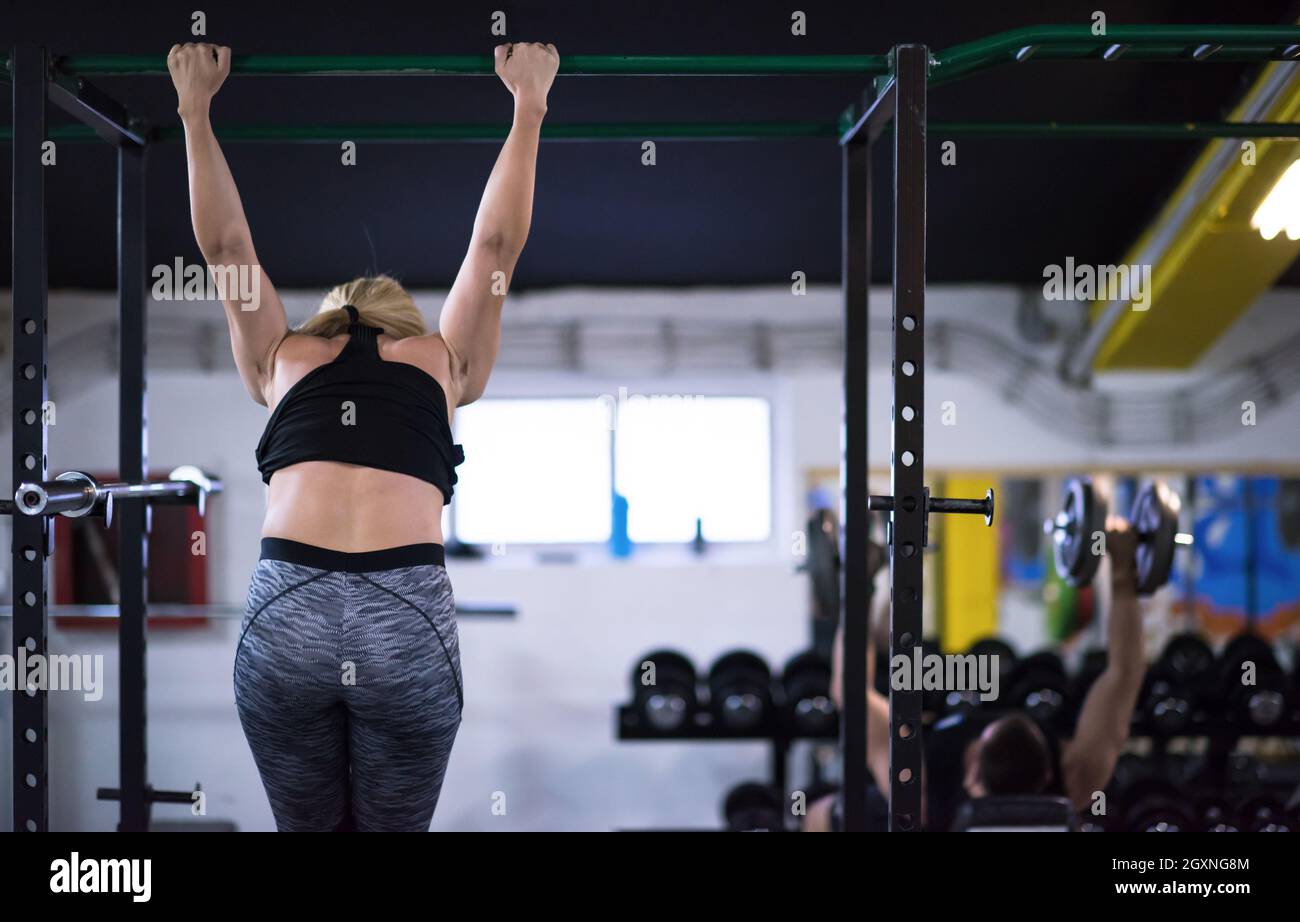 athlete woman doing abs exercises hanging upside down on horizontal bar ...
