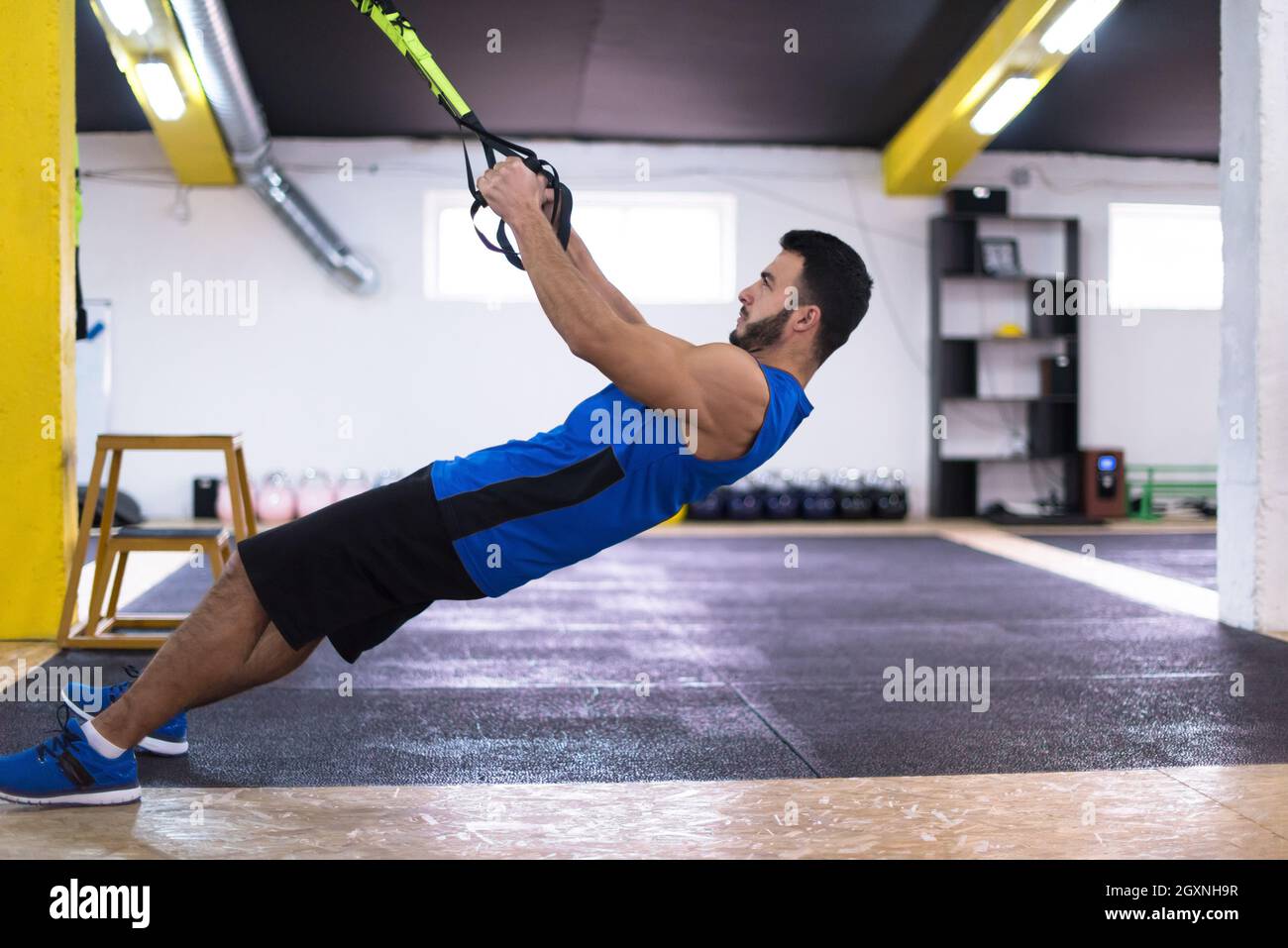 young athlete man working out pull ups with gymnastic rings at the ...