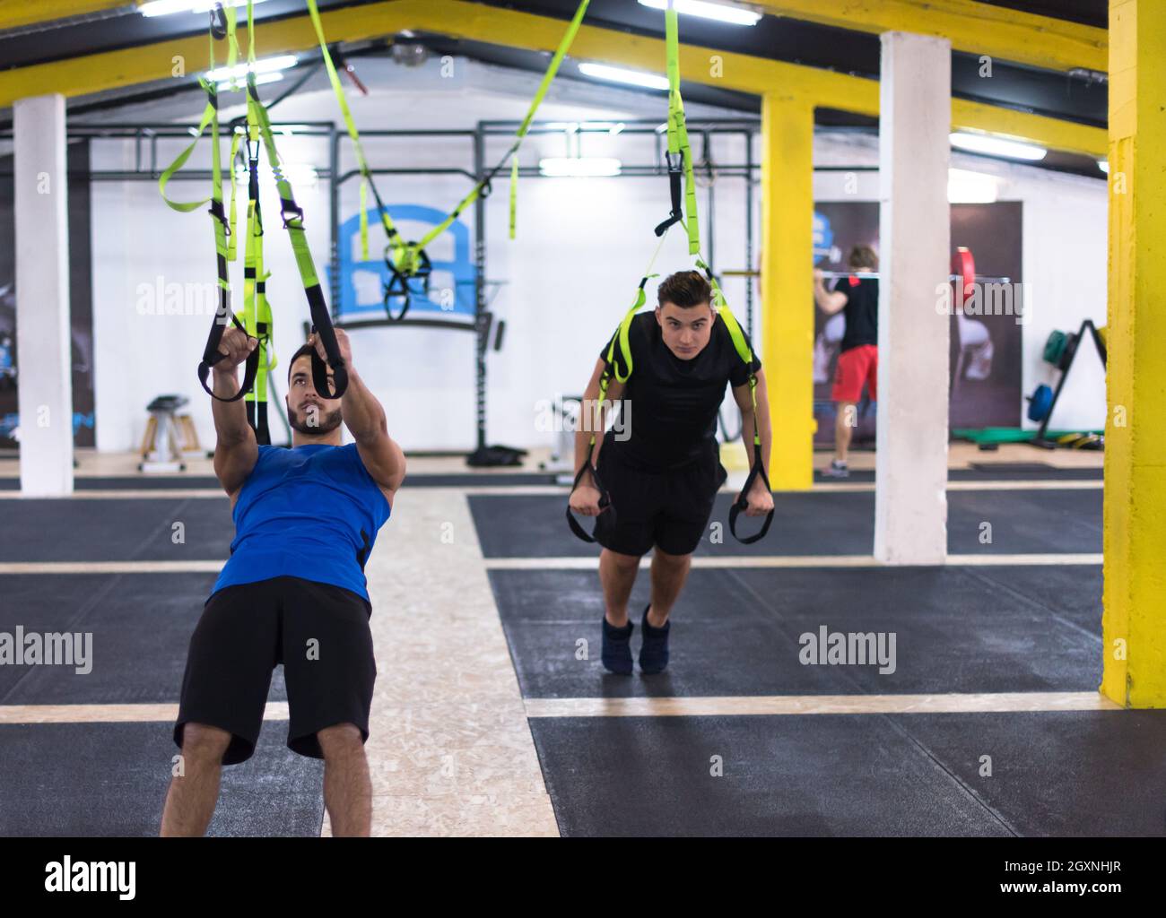two young athlete men working out pull ups with gymnastic rings at the ...