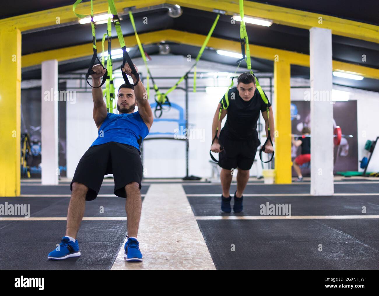 two young athlete men working out pull ups with gymnastic rings at the ...