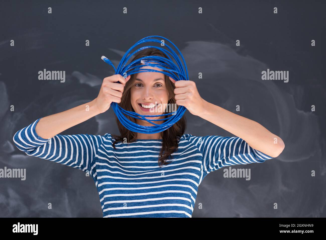 portrait of a young woman holding a internet cable in front of chalk ...