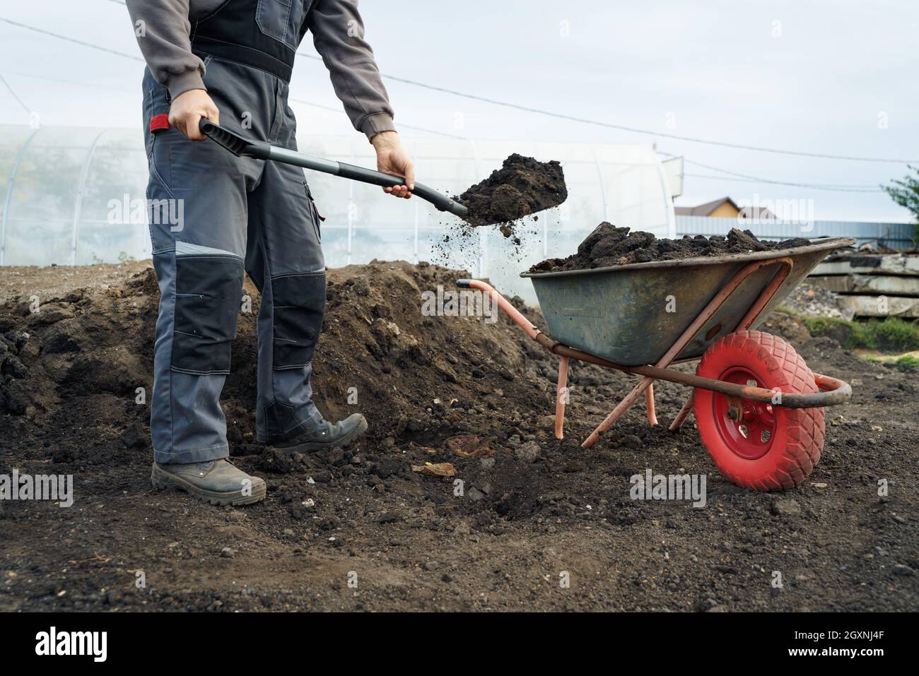 Working with garden tools, shovel and wheelbarrow on the site of a ...