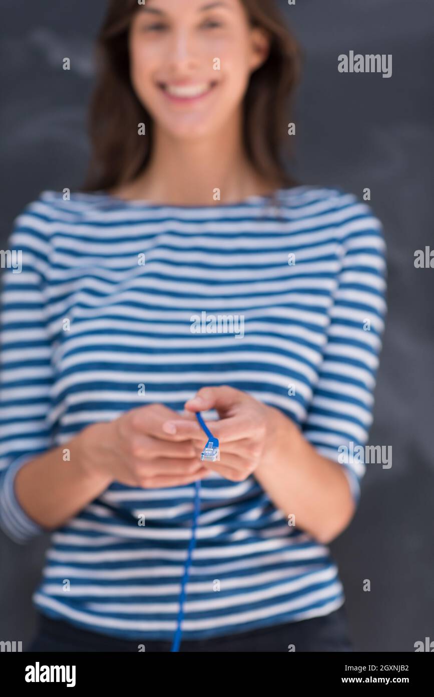 portrait of a young woman holding a internet cable in front of chalk ...