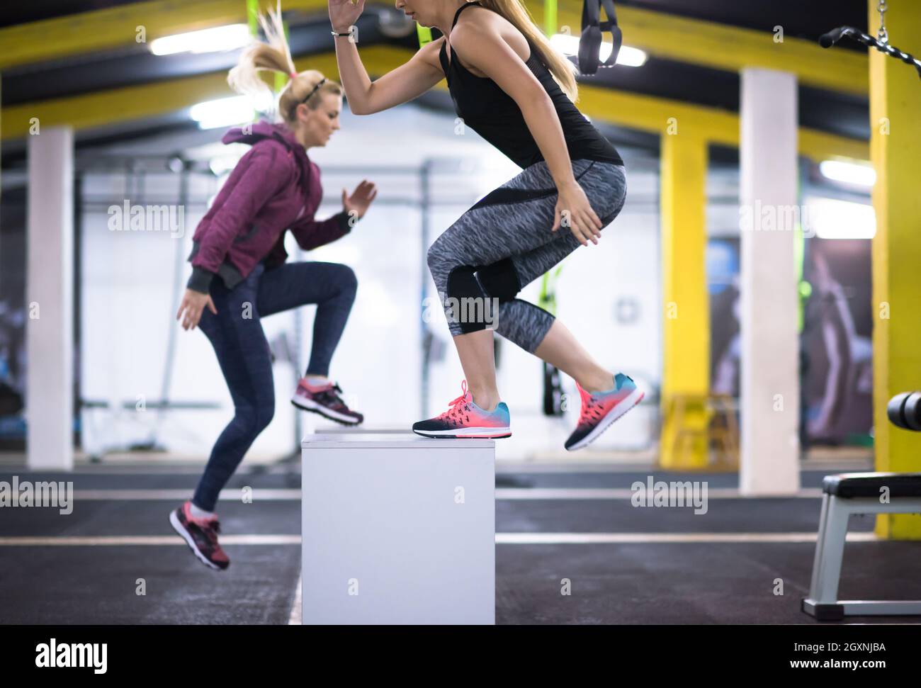 group of young healthy athletic people training jumping on fit box at ...