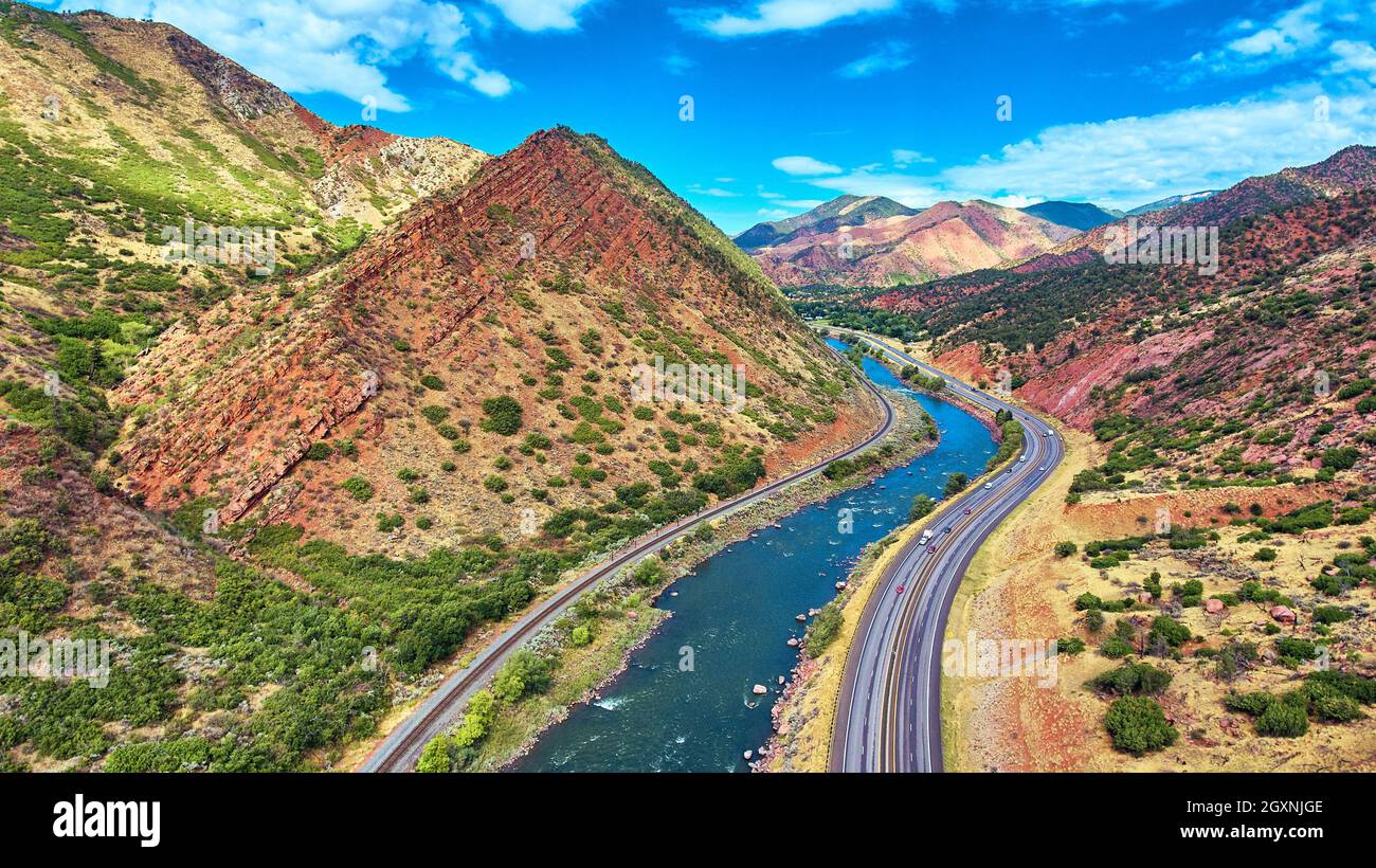 Layered red rock mountains in valley with river, highway, and train ...