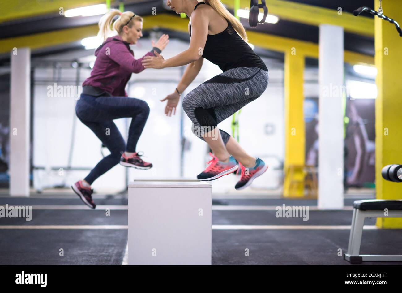 group of young healthy athletic people training jumping on fit box at ...