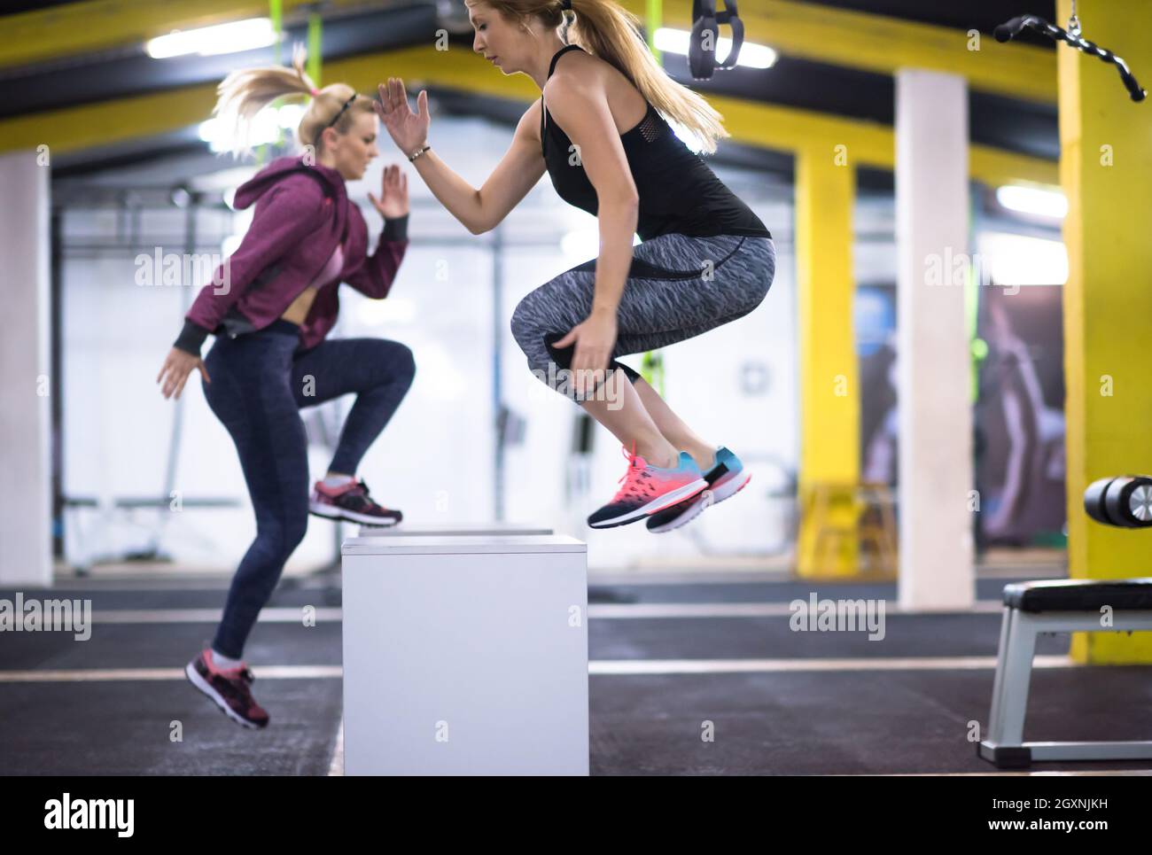 group of young healthy athletic people training jumping on fit box at ...