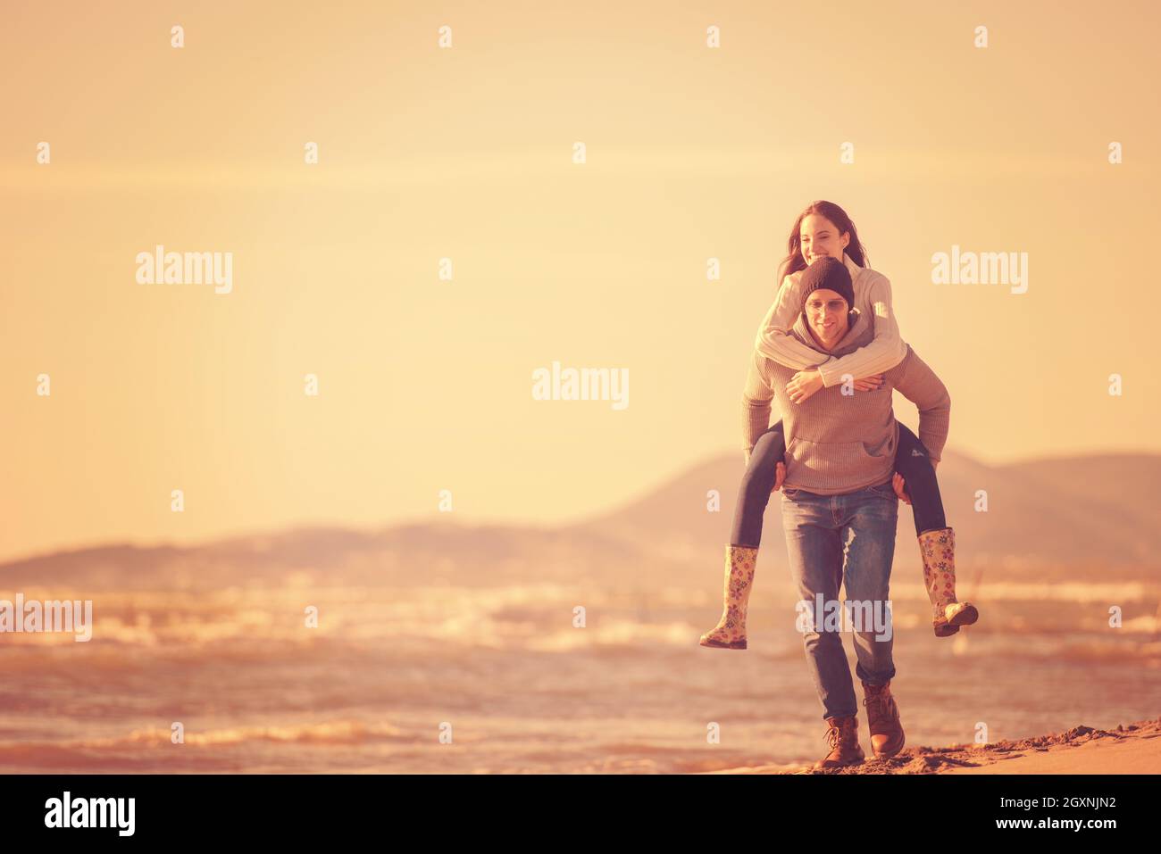 Men Giving Piggy Back Rides his girlfriend At Sunset By The Sea, autumn time Stock Photo - Alamy
