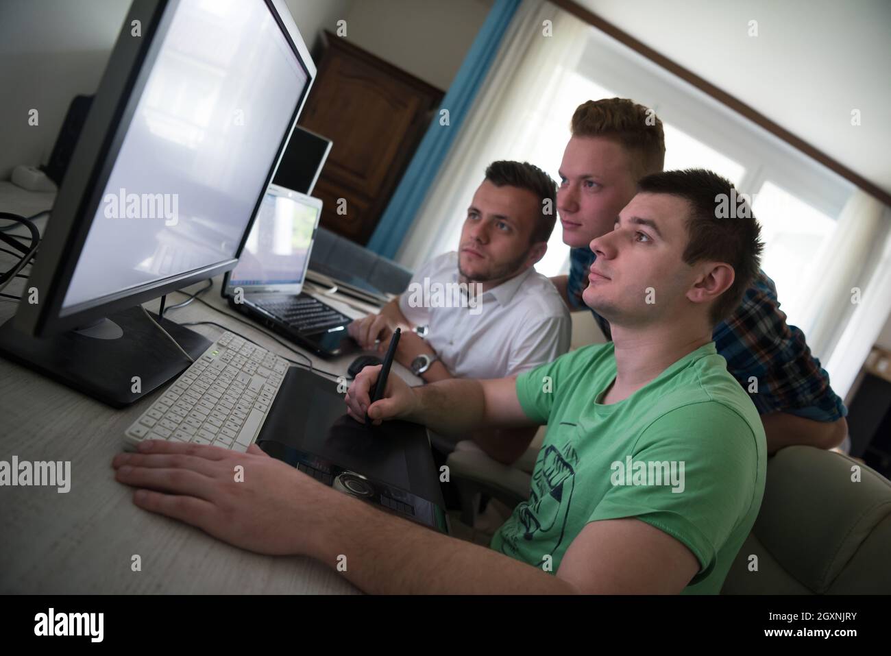 a group of young graphic designers working on a digital tablet and a ...