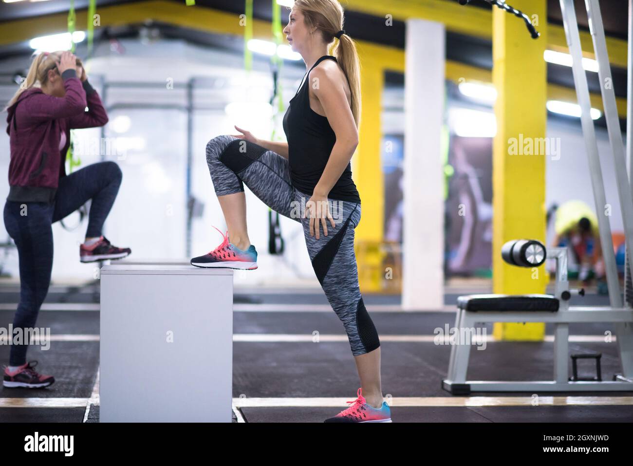 group of young healthy athletic people training jumping on fit box at ...
