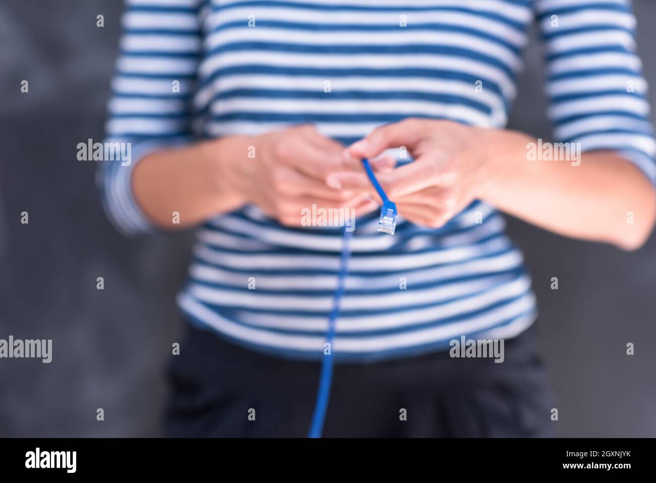 portrait of a young woman holding a internet cable in front of chalk ...