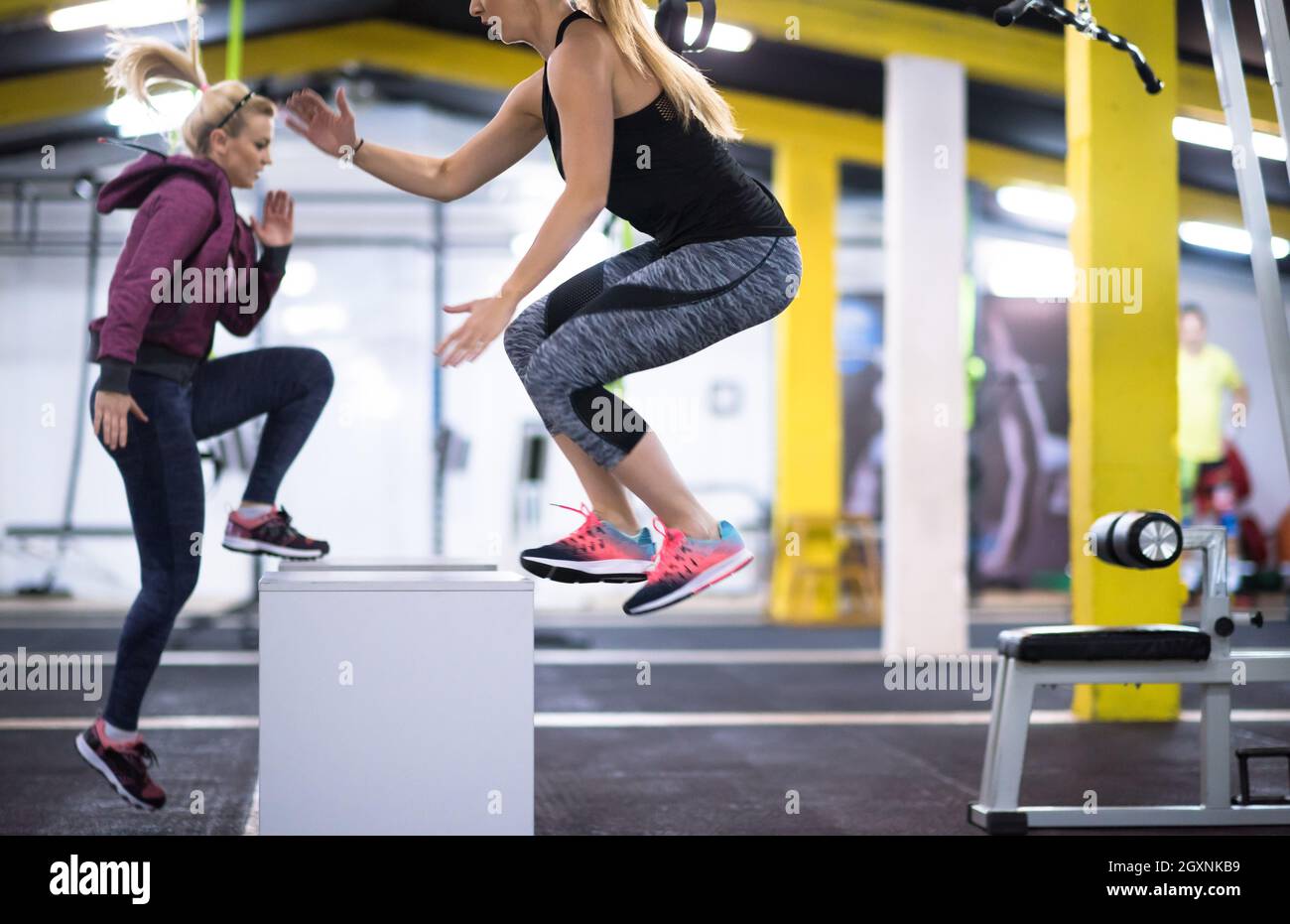 group of young healthy athletic people training jumping on fit box at ...