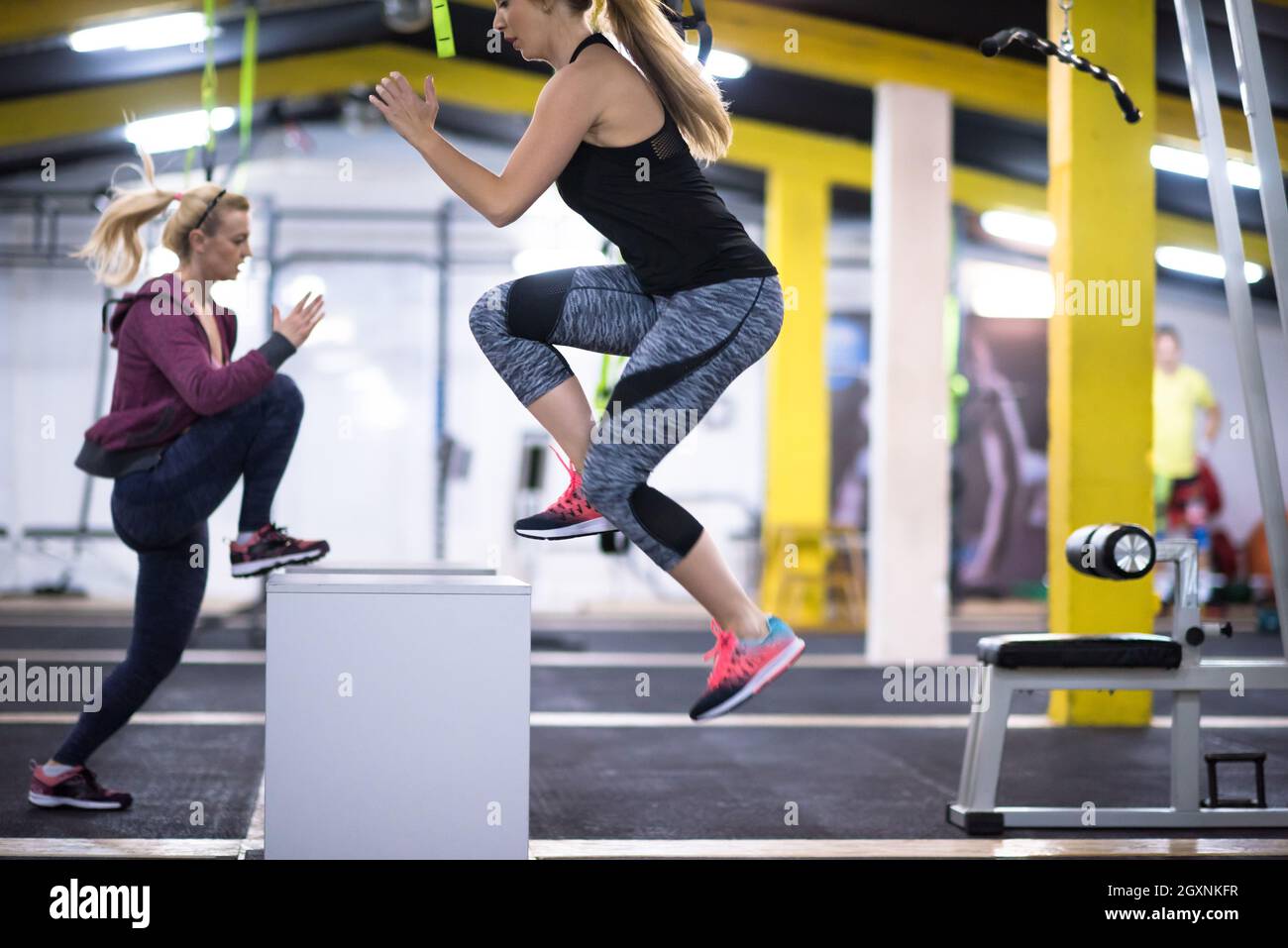 group of young healthy athletic people training jumping on fit box at ...