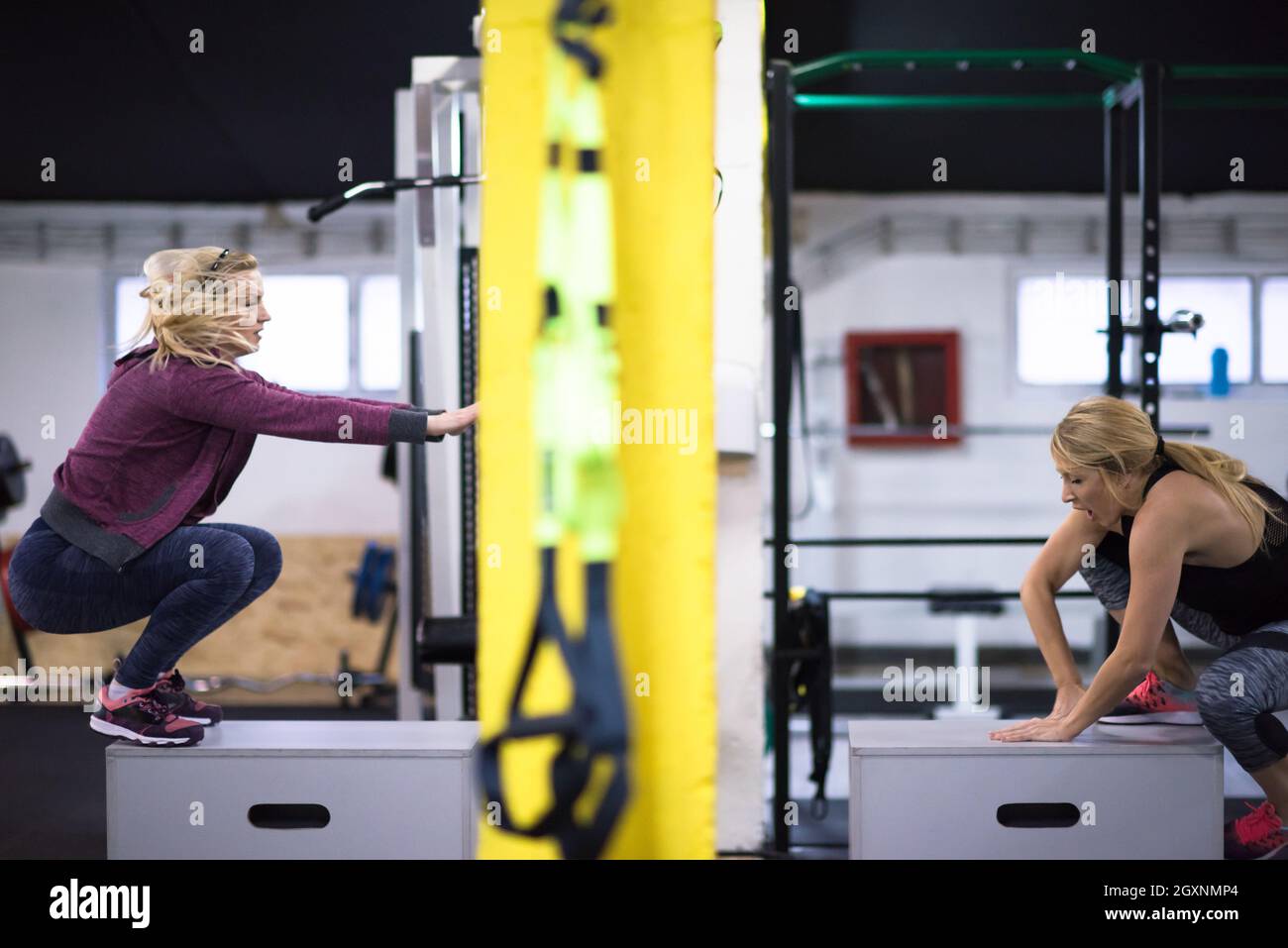 group of young healthy athletic people training jumping on fit box at ...