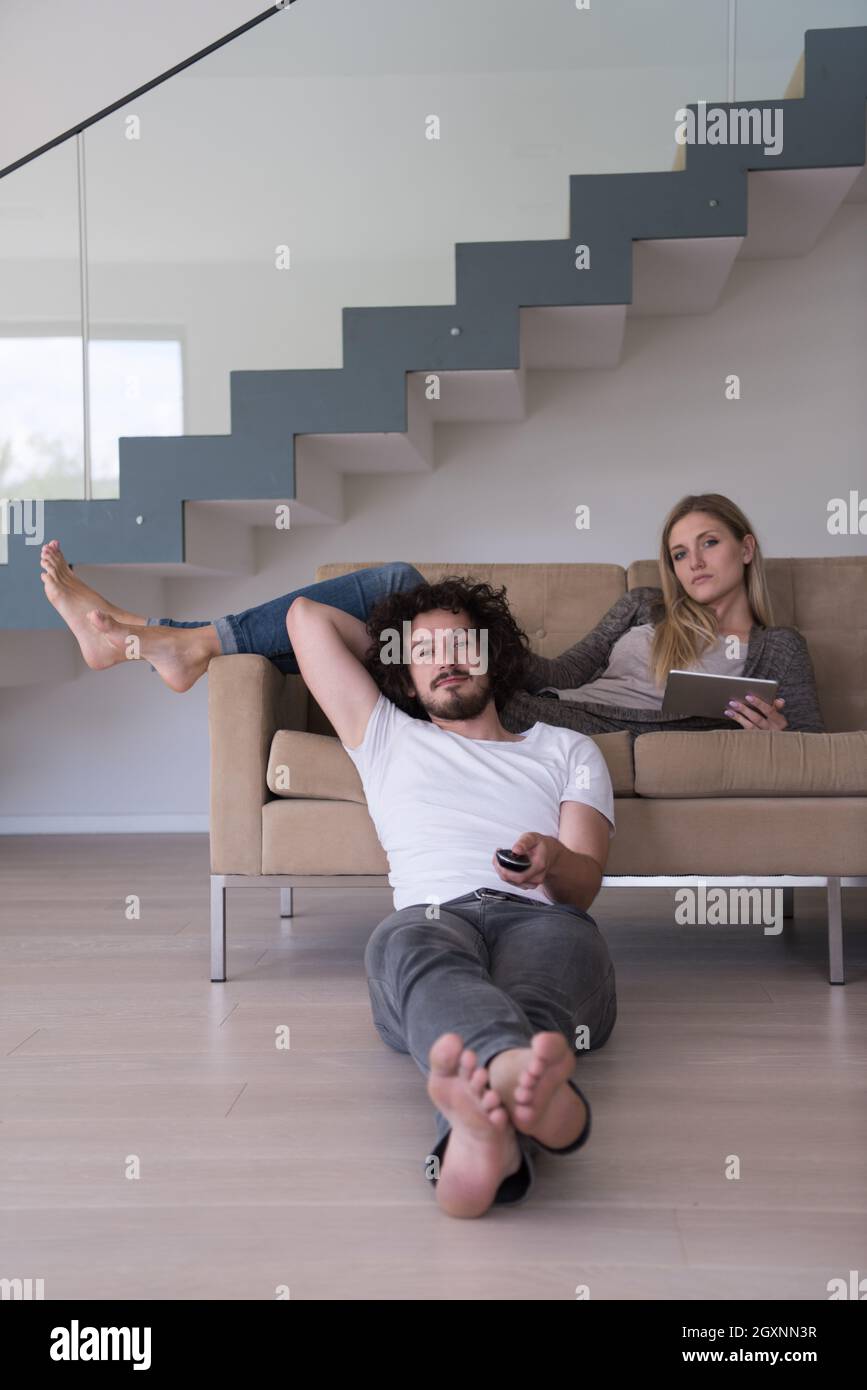 Young couple relaxes on the sofa in the luxury living room, using a ...