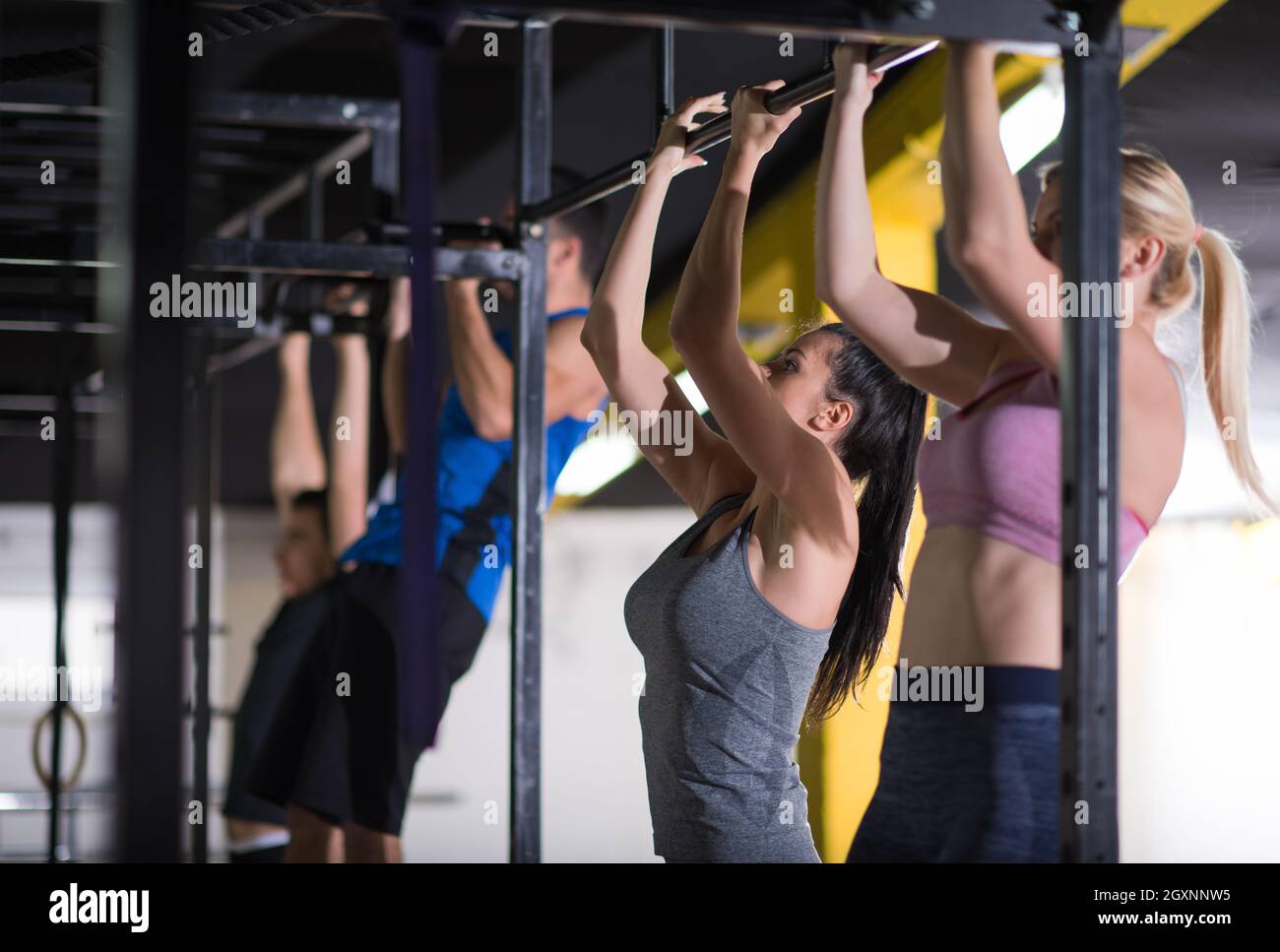 group of young muscular athletes doing pull ups on the horizontal bar ...