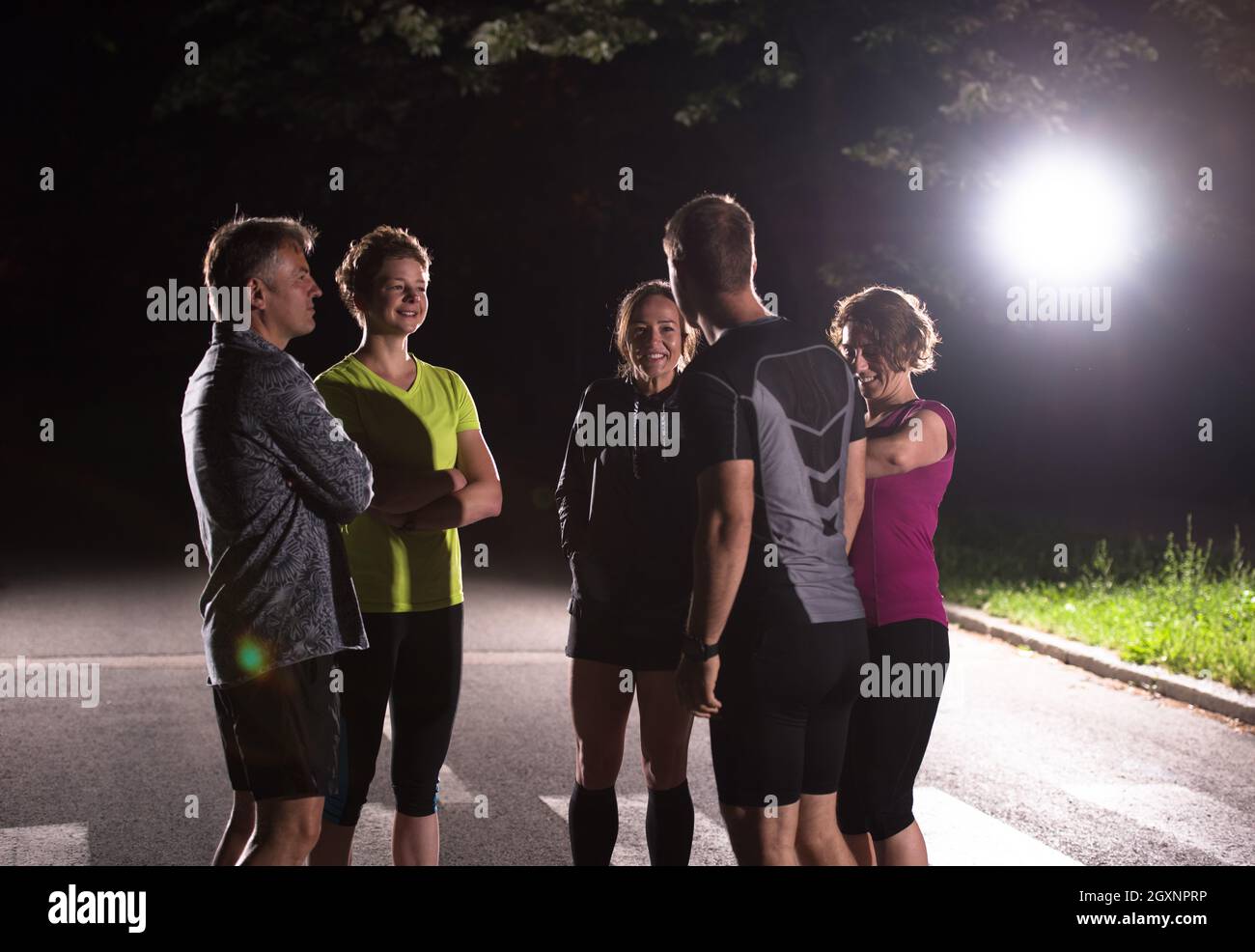 group of healthy people jogging in city park, runners team at night ...