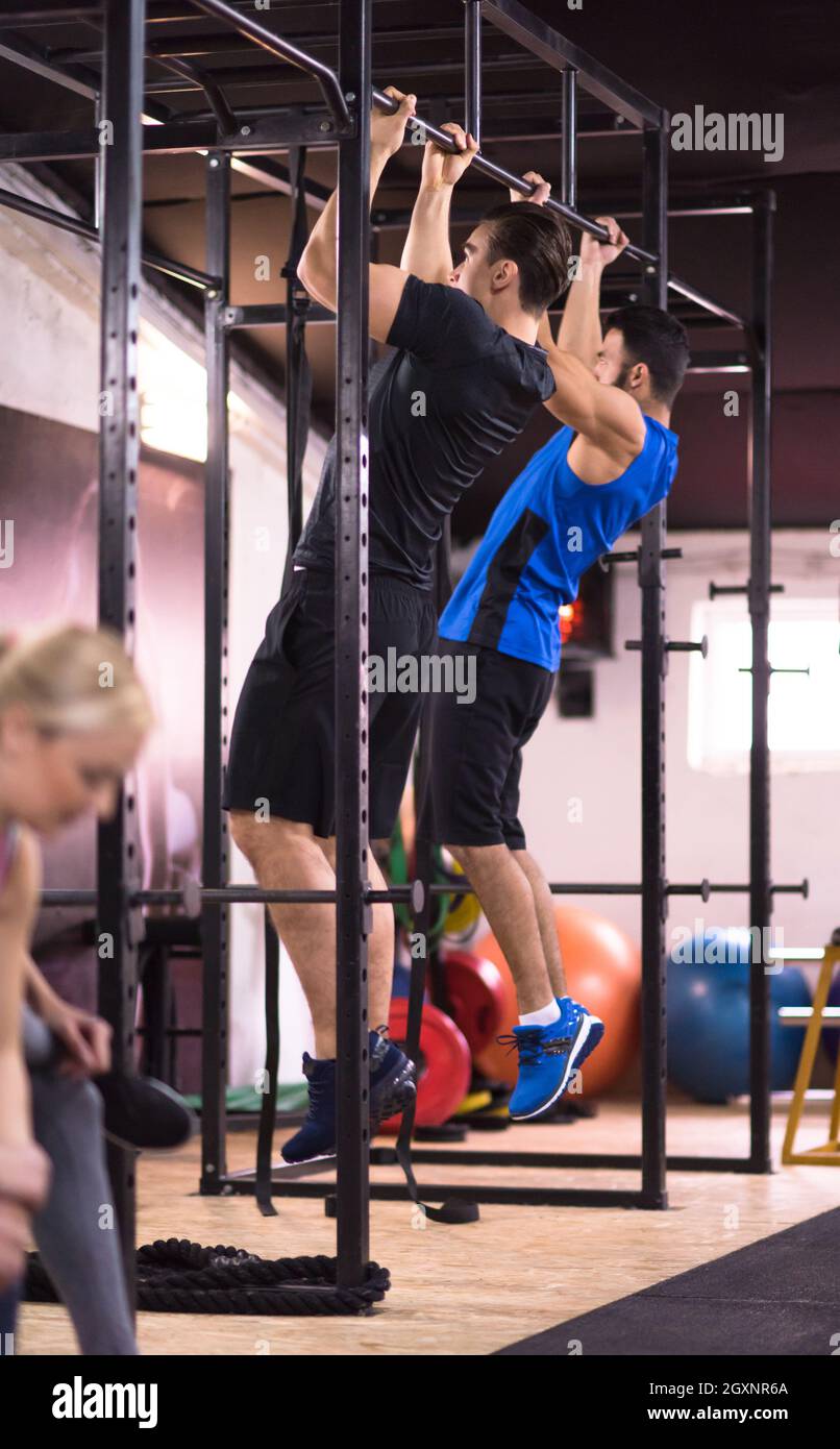 group of young muscular athletes doing pull ups on the horizontal bar ...