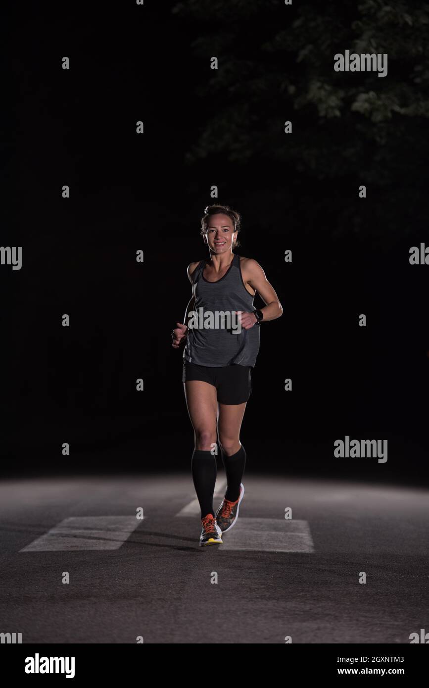 fit muscular female runner training for marathon running at night on ...
