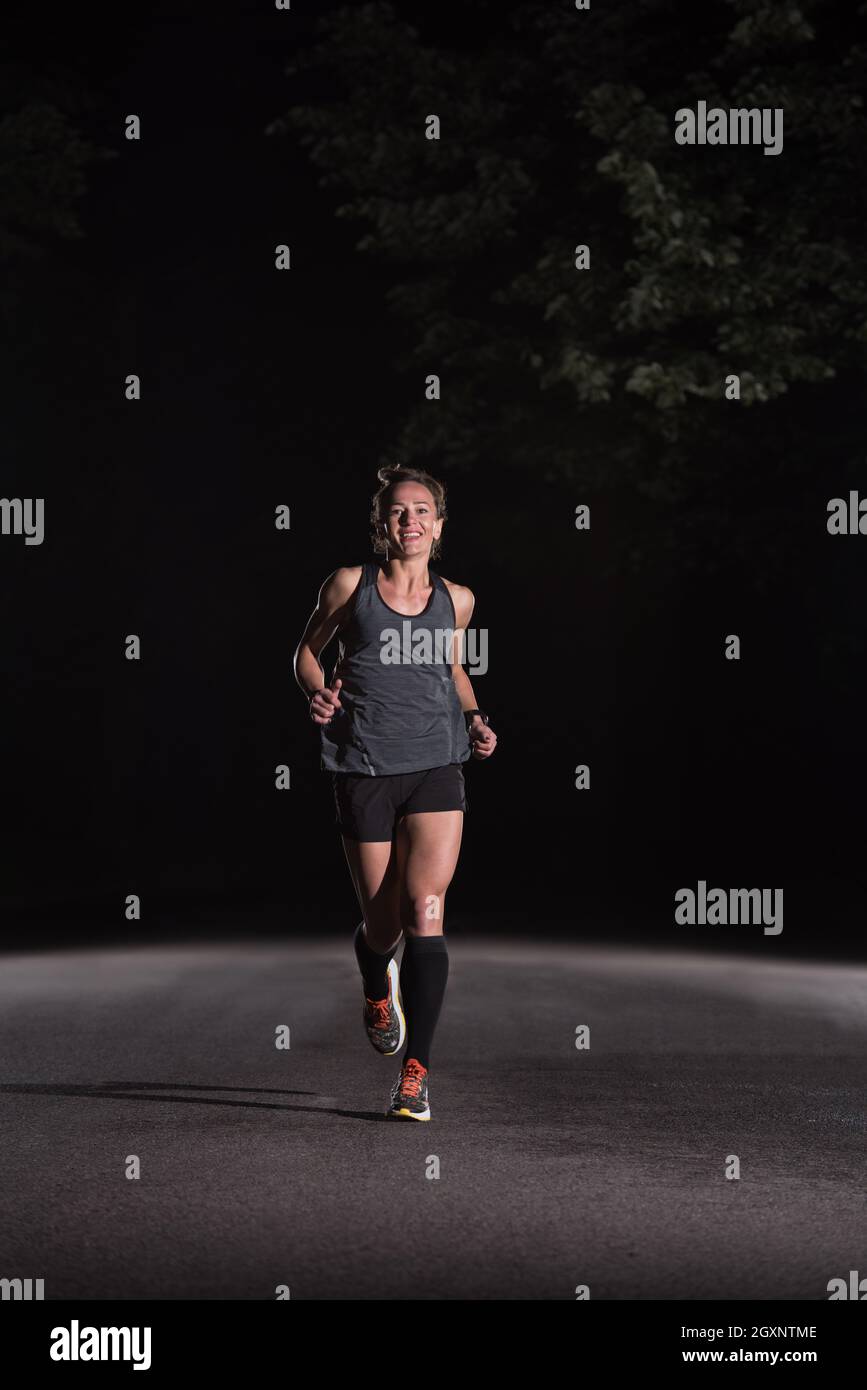 fit muscular female runner training for marathon running at night on ...