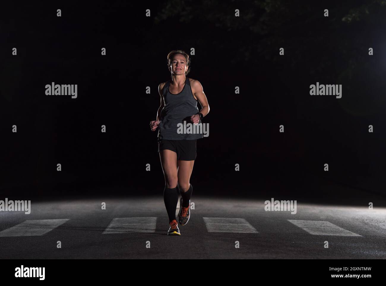 fit muscular female runner training for marathon running at night on ...