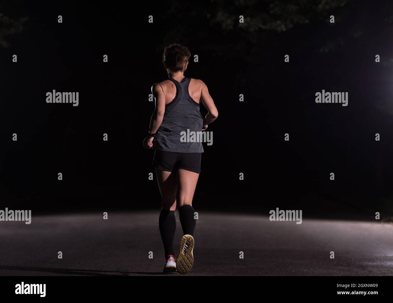 fit muscular female runner training for marathon running at night on ...