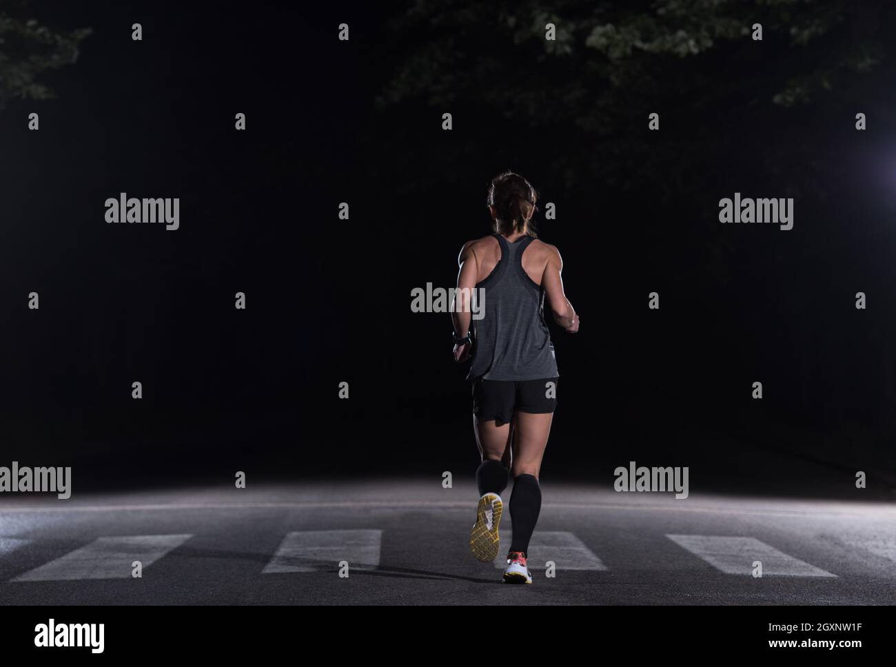 fit muscular female runner training for marathon running at night on ...