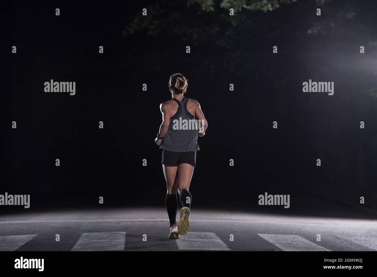 fit muscular female runner training for marathon running at night on ...