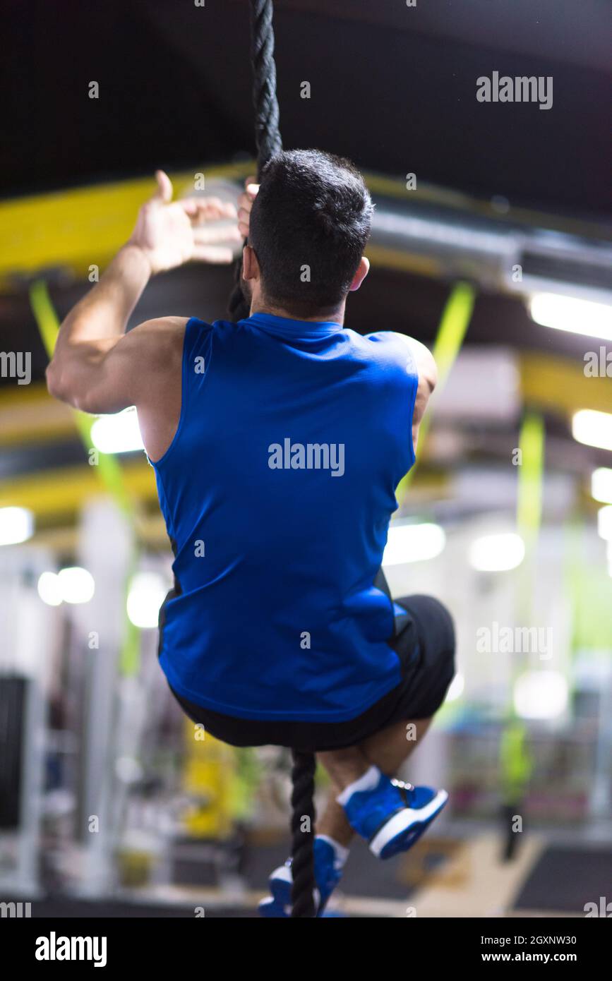 young muscular man doing rope climbing in cross fitness gym Stock Photo ...