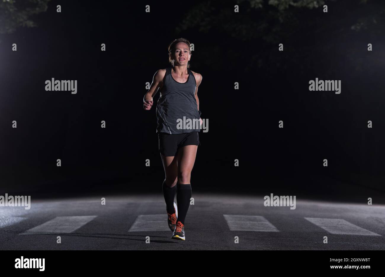fit muscular female runner training for marathon running at night on ...