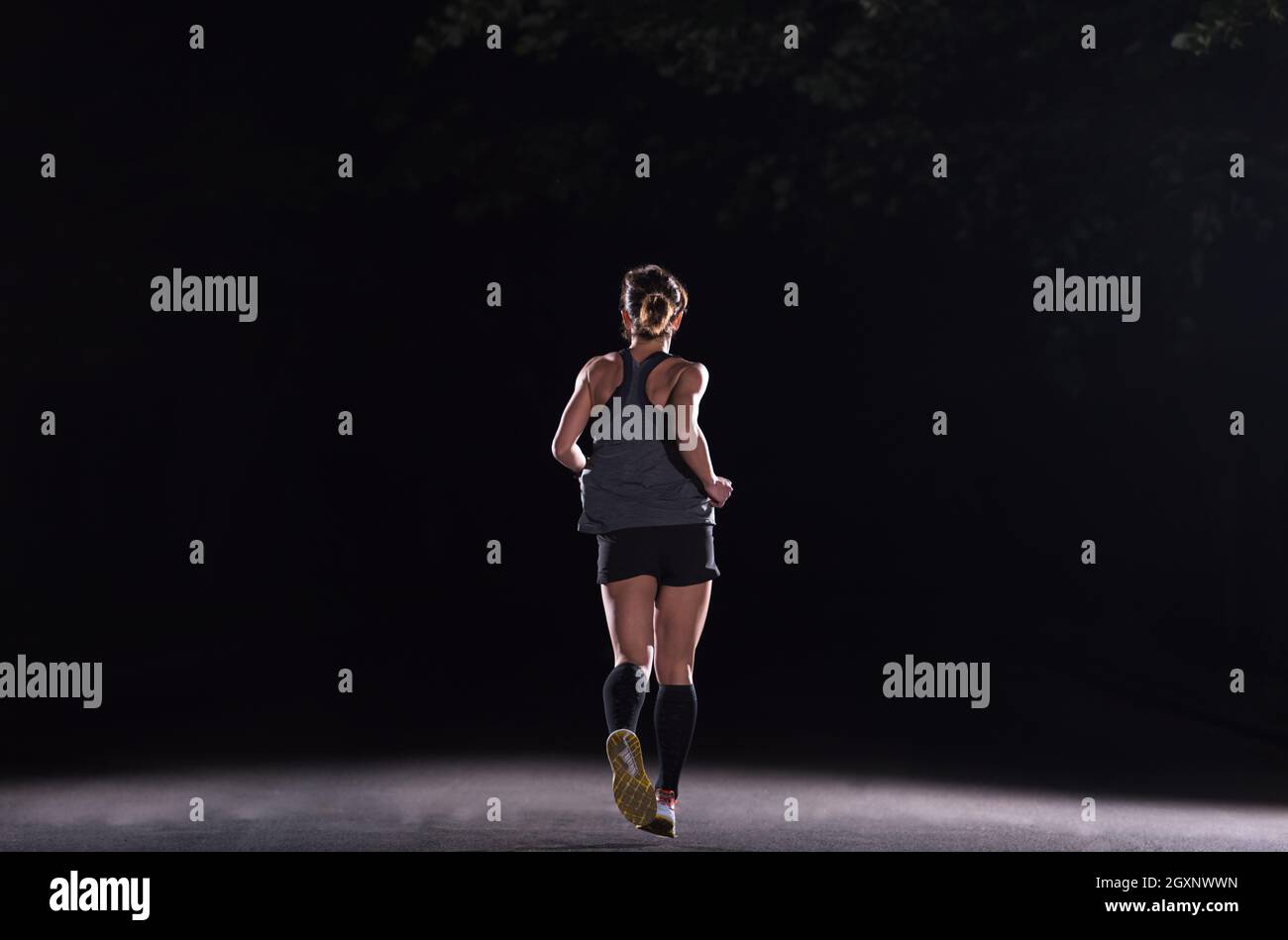 fit muscular female runner training for marathon running at night on ...