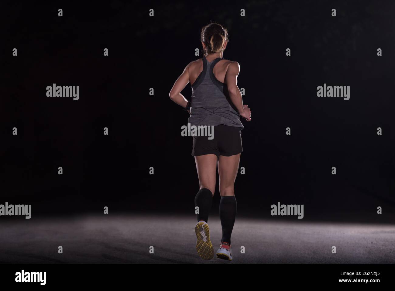 fit muscular female runner training for marathon running at night on ...