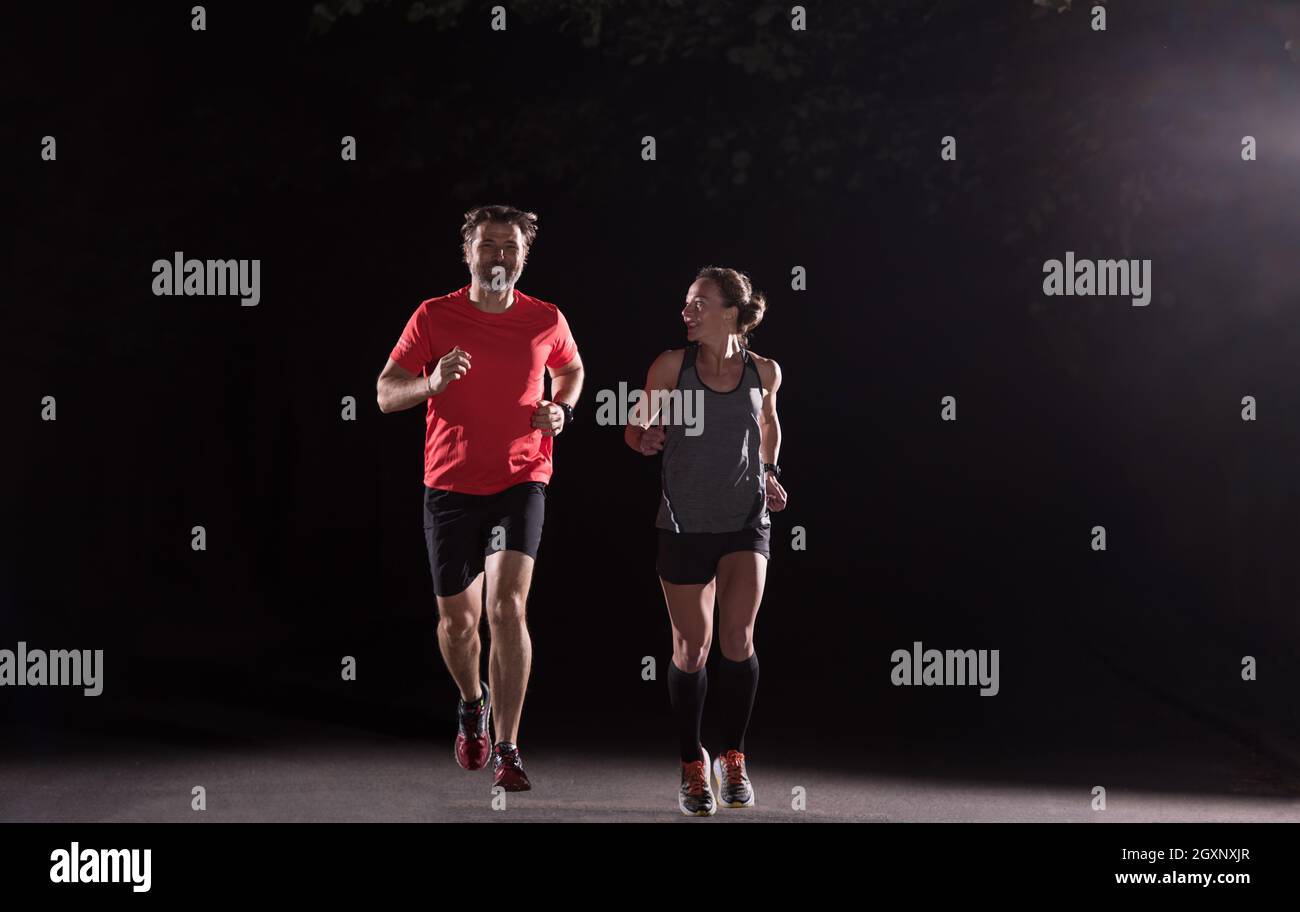 group of healthy people jogging in city park, runners team at night ...