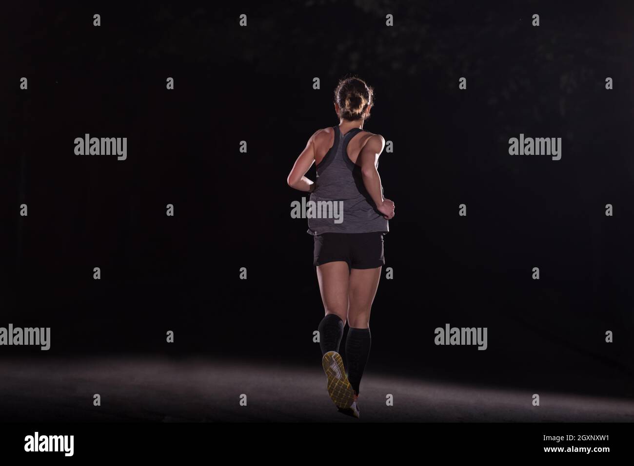 fit muscular female runner training for marathon running at night on ...