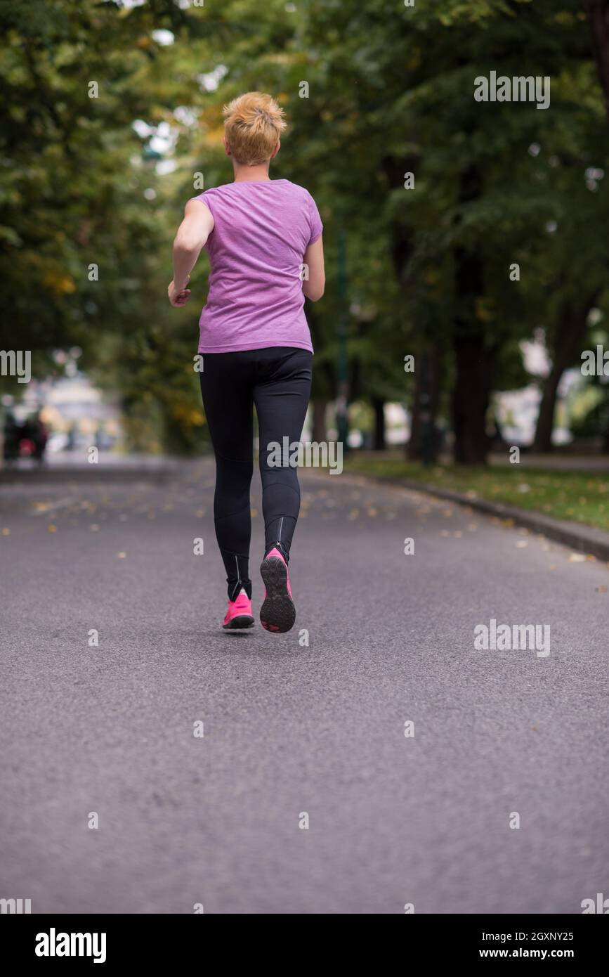 fit muscular female runner training for marathon running at morning on ...