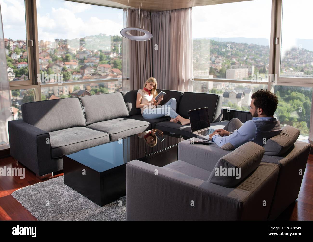 Young couple relaxing at home using tablet and laptop computers reading ...