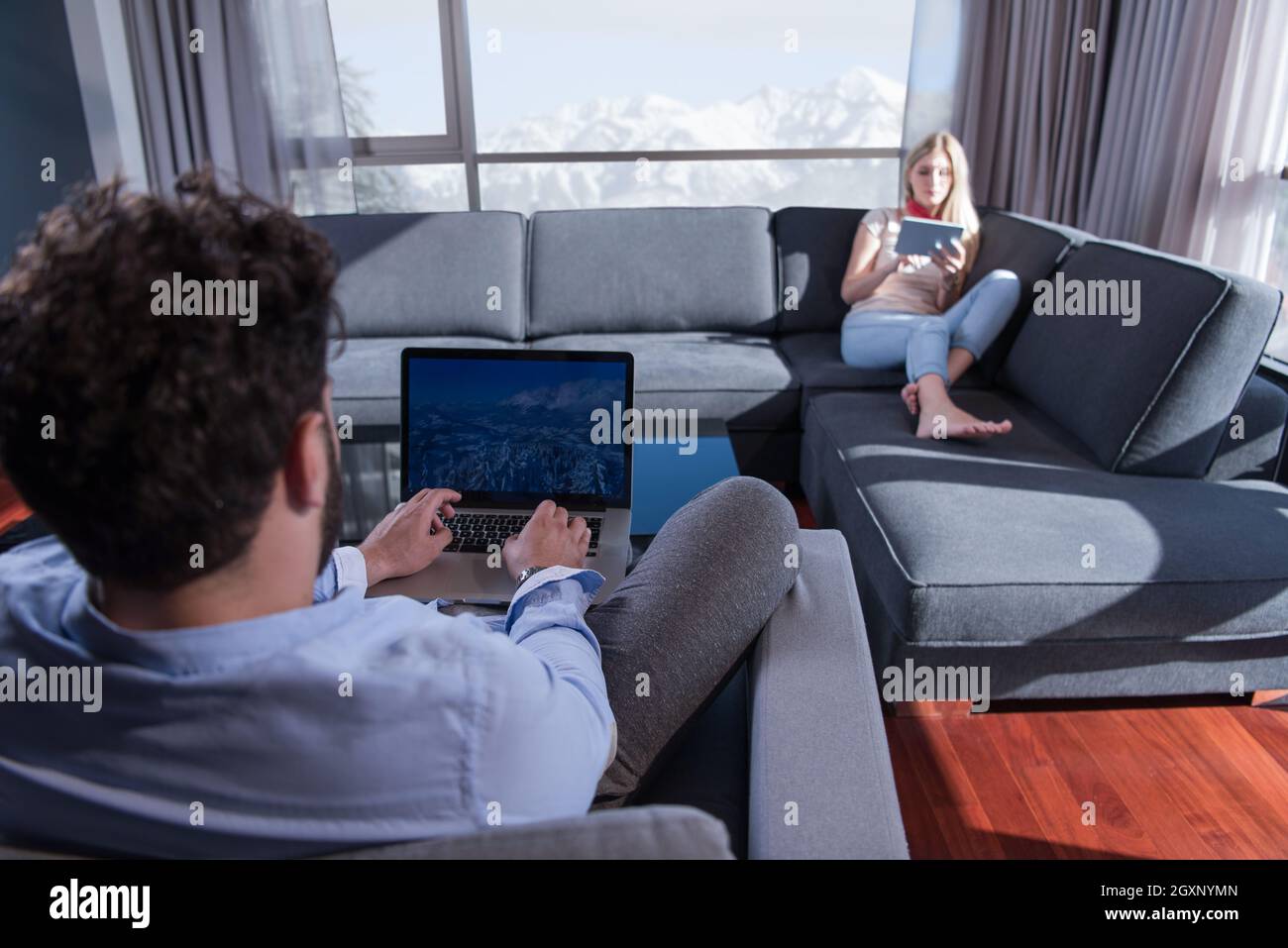 Young couple relaxing at home using tablet and laptop computers reading ...