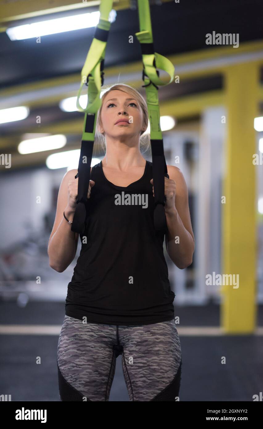 young athlete woman working out pull ups with gymnastic rings at the ...
