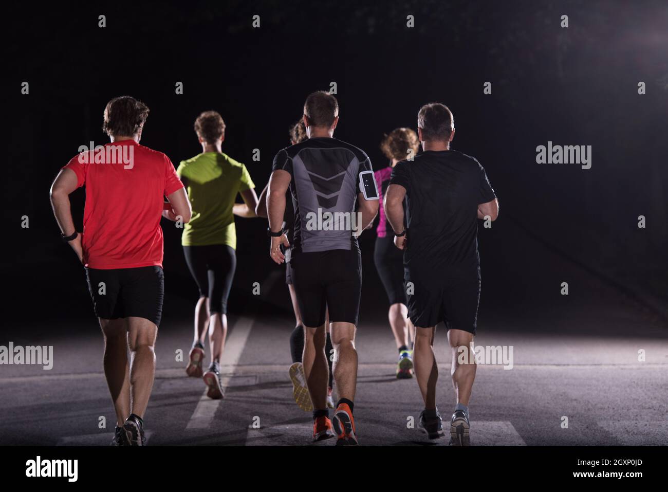 group of healthy people jogging in city park, runners team at night ...