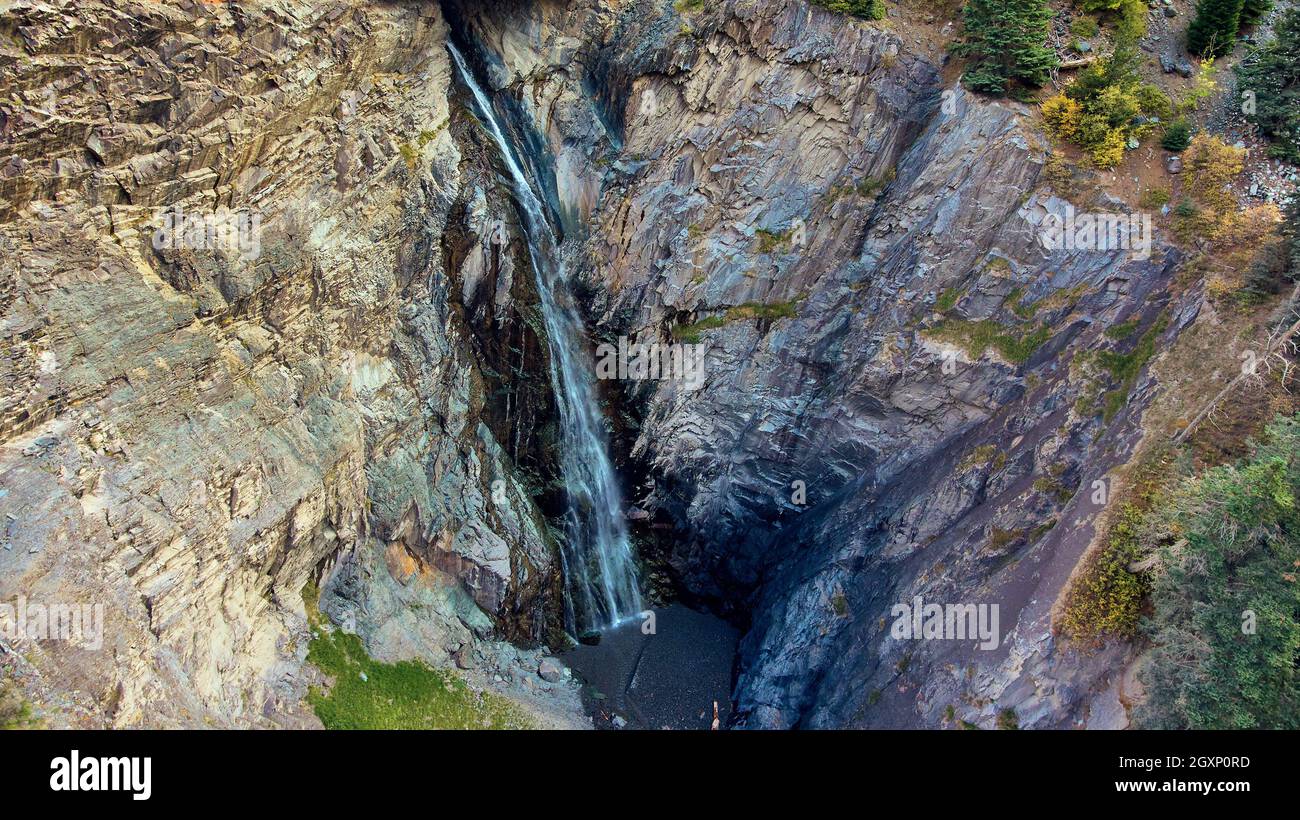 Waterfall pouring into small pond along cliff edge Stock Photo - Alamy