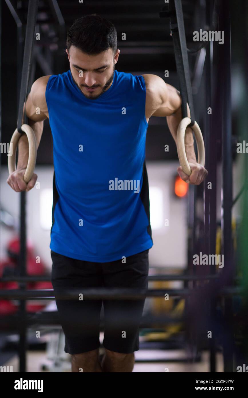 young athlete man working out pull ups with gymnastic rings at the ...