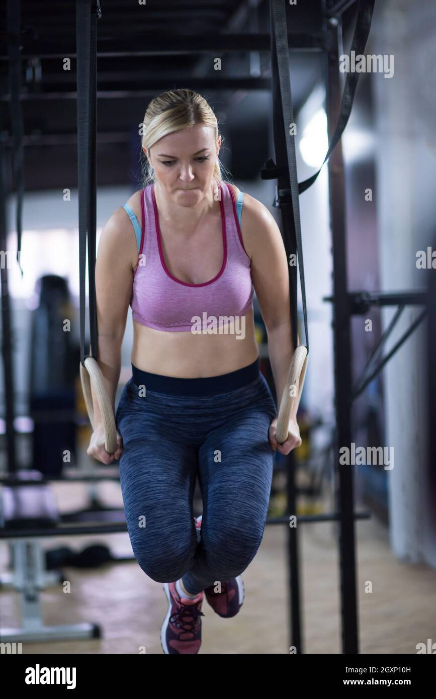 young athlete woman working out pull ups with gymnastic rings at the ...