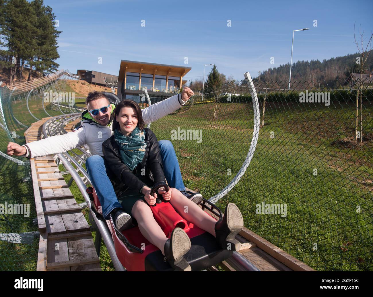 Excited young couple enjoys driving on alpine coaster Stock Photo - Alamy