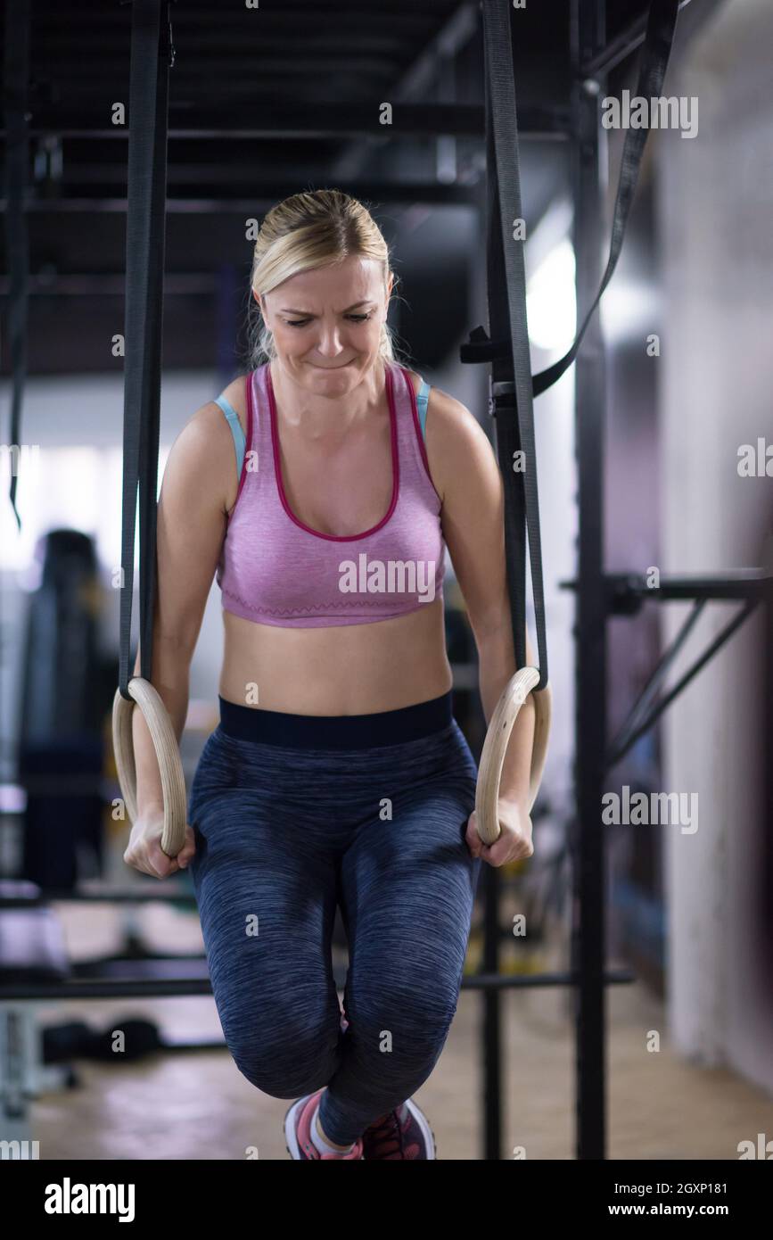 young athlete woman working out pull ups with gymnastic rings at the ...